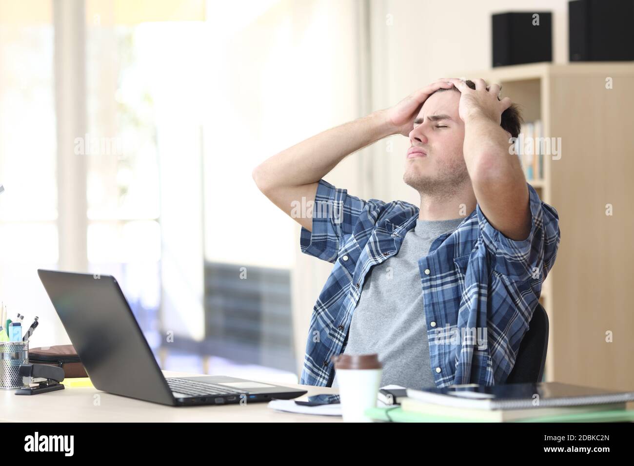 Sad student man with laptop complaining sitting on a desk at the office ...