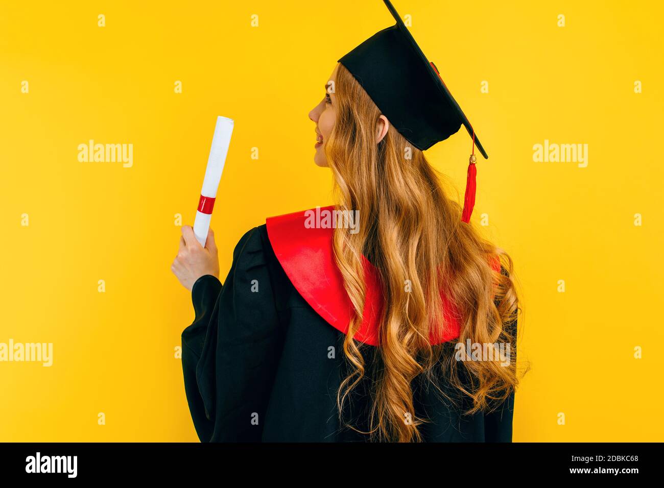 Back view of a female graduate with a diploma in her hands, on an ...