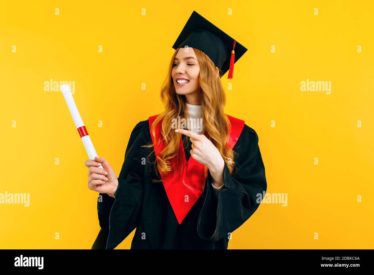 Happy attractive graduate in a master's dress, with a diploma on a ...