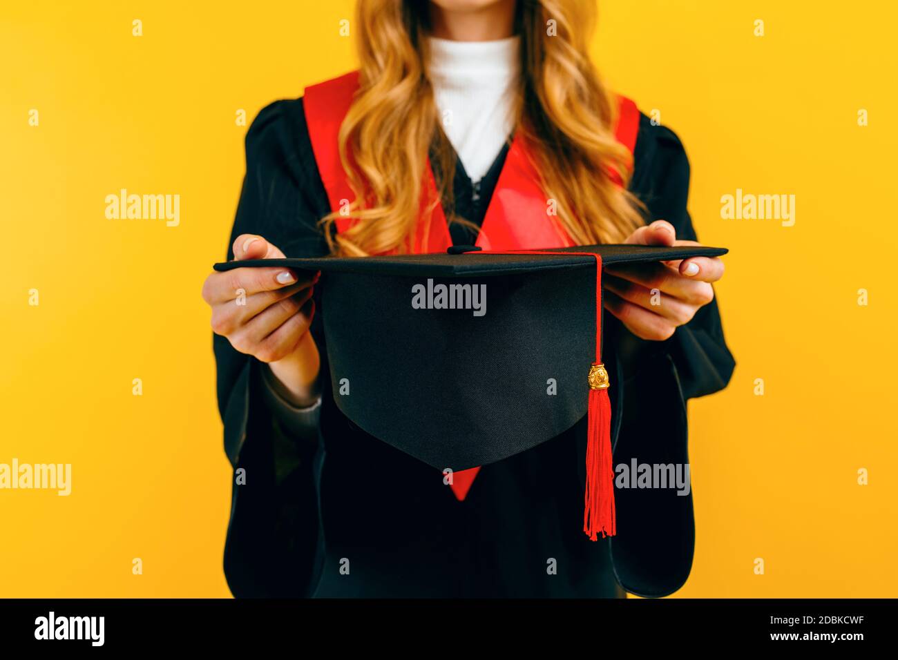 Student with a graduation hat in hand, on a yellow background, close-up ...