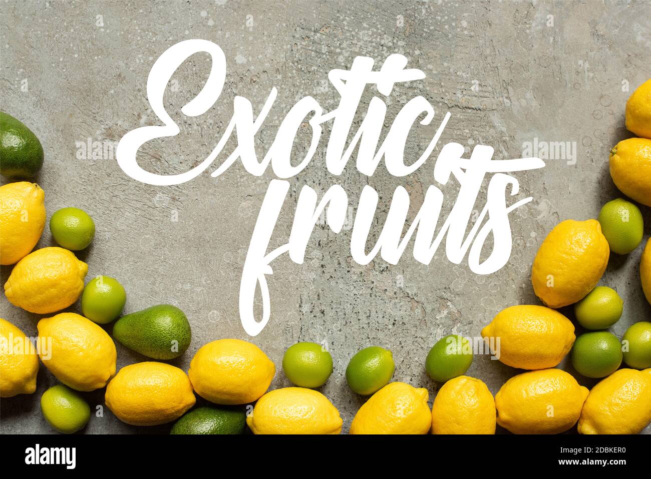 top view of colorful avocado, limes and lemons on grey concrete surface ...