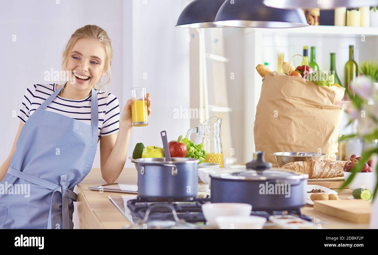 Beautiful woman in kitchen is drinking red wine Stock Photo - Alamy