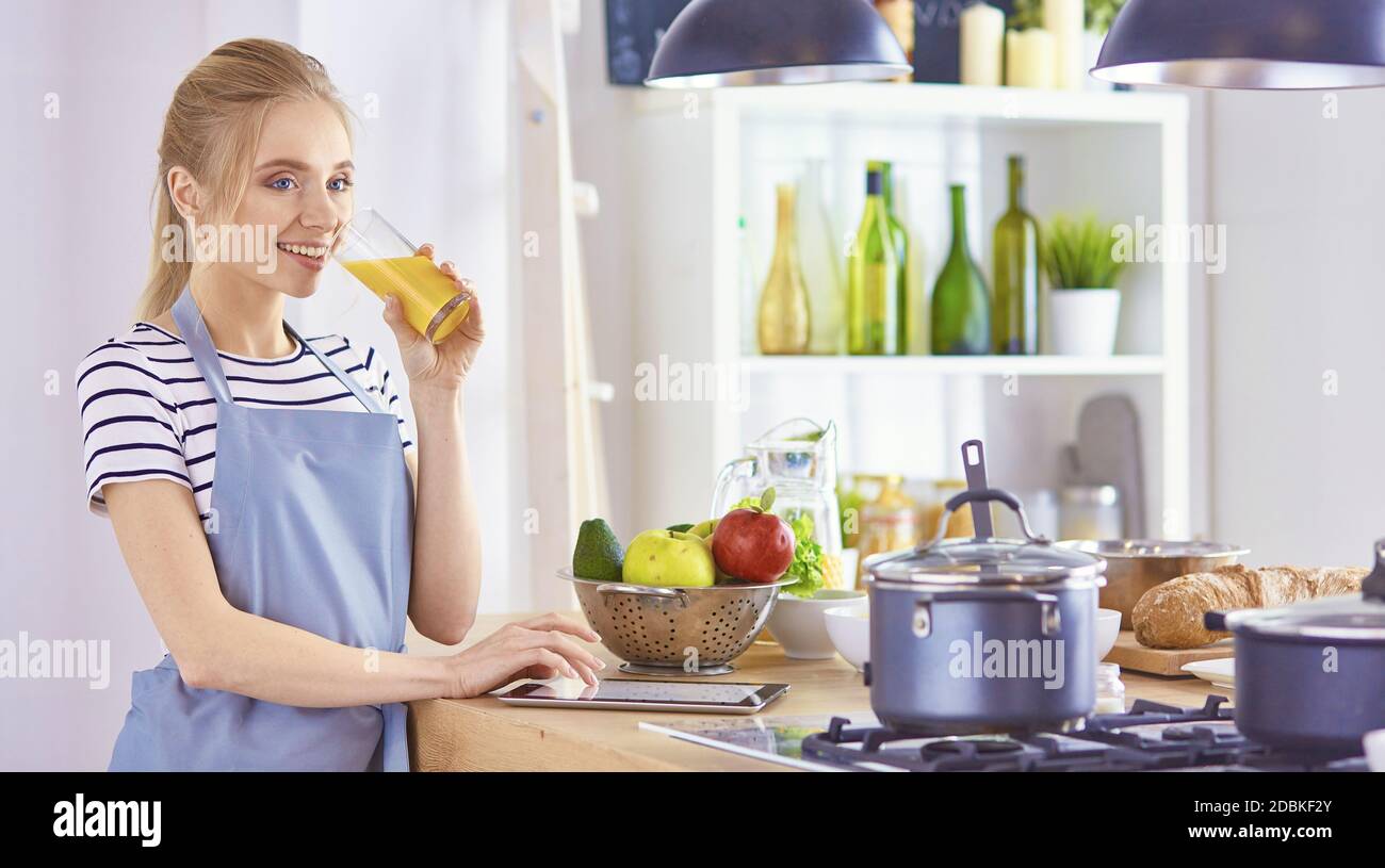 Beautiful woman in kitchen is drinking red wine Stock Photo - Alamy