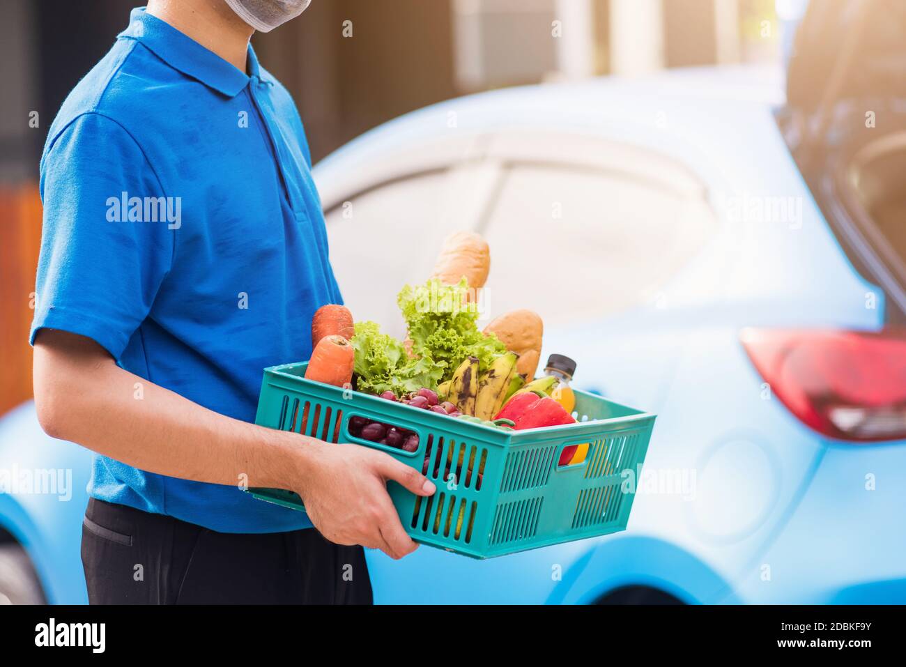 Asian grocery store delivery man wearing blue uniform and face mask ...