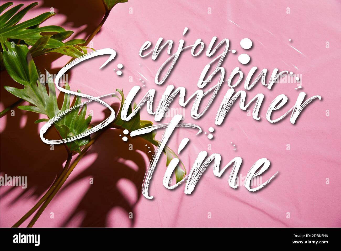 top view of fresh tropical green leaves on pink plastic background with ...