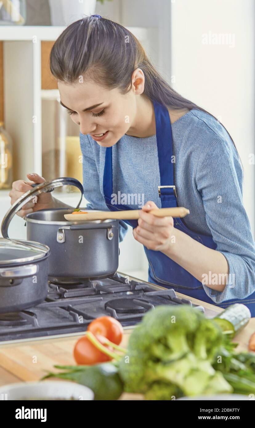 Beautiful woman in the kitchen, waiting with the front of the oven ...