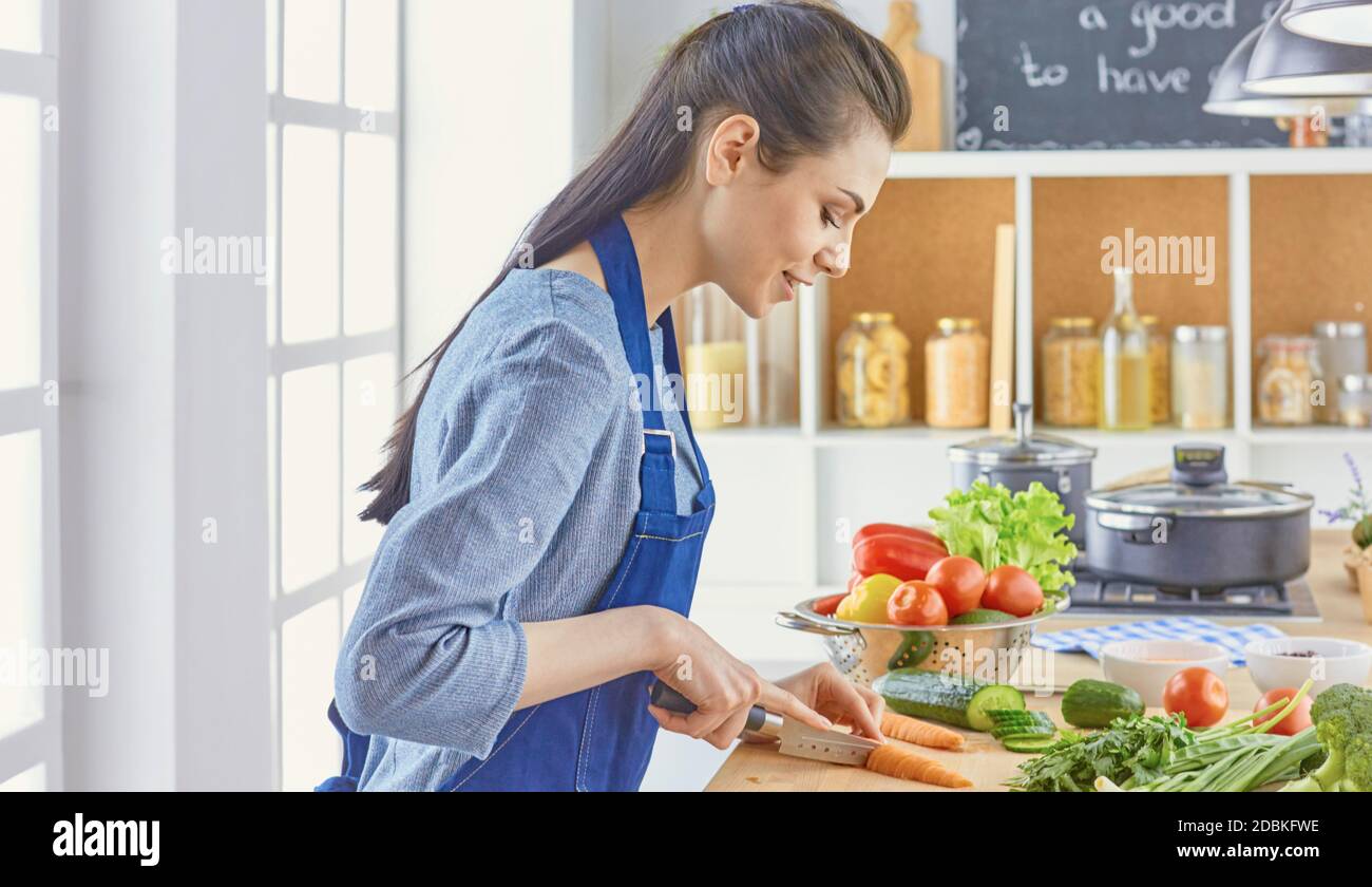 Beautiful woman in the kitchen, waiting with the front of the oven ...