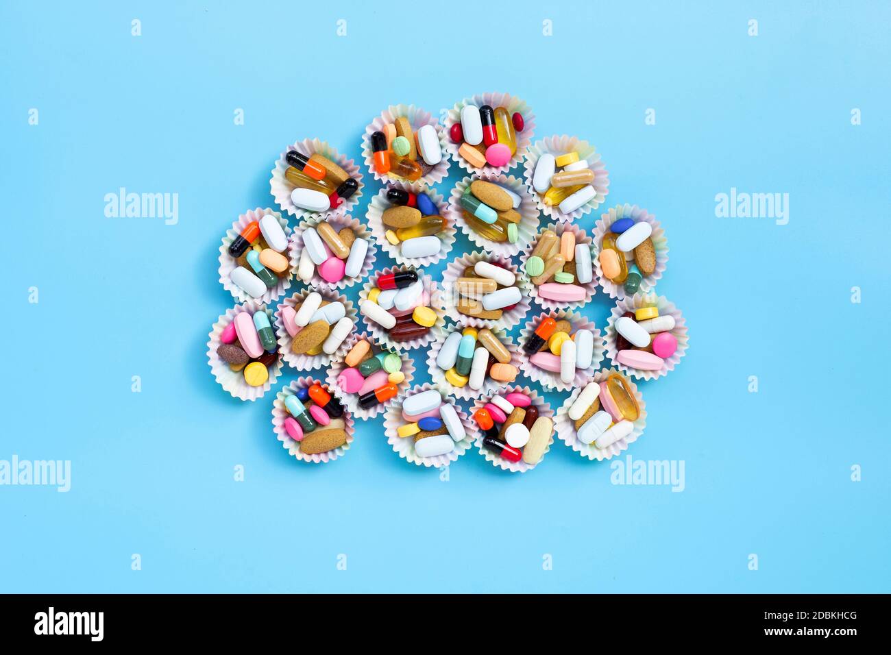 Colorful tablets with capsules and pills in cupcake wrappers on blue ...