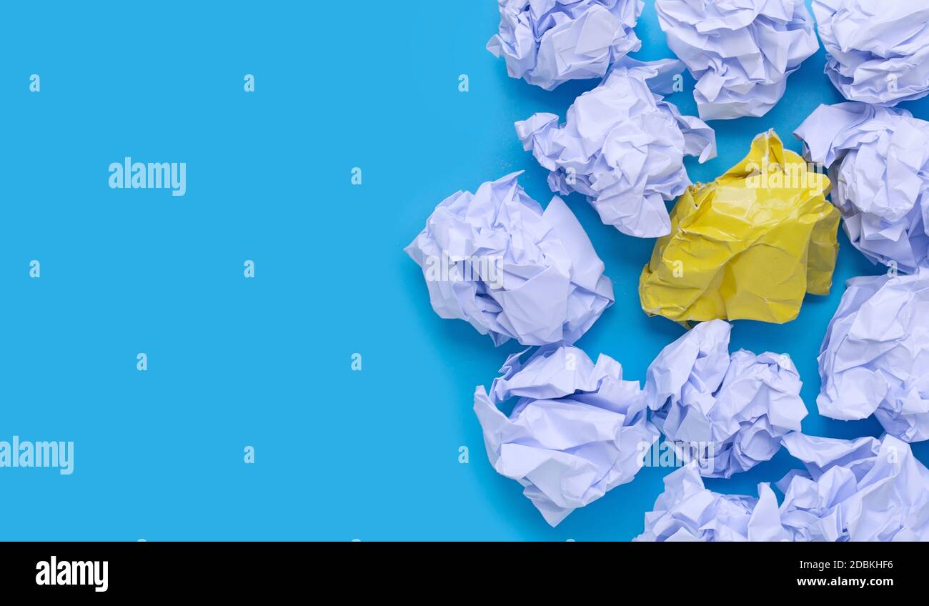 White and yellow crumpled paper balls on a blue background. Top view ...