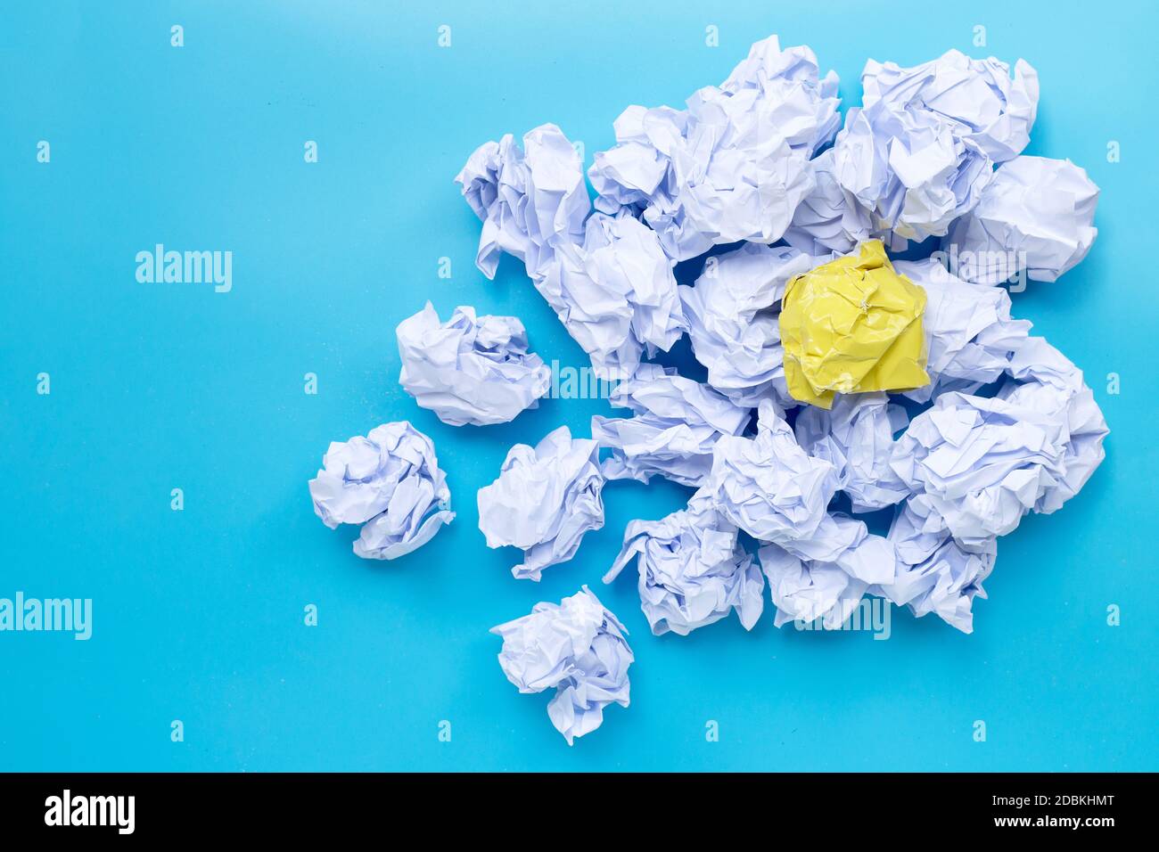 White and yellow crumpled paper balls on a blue background. Top view ...