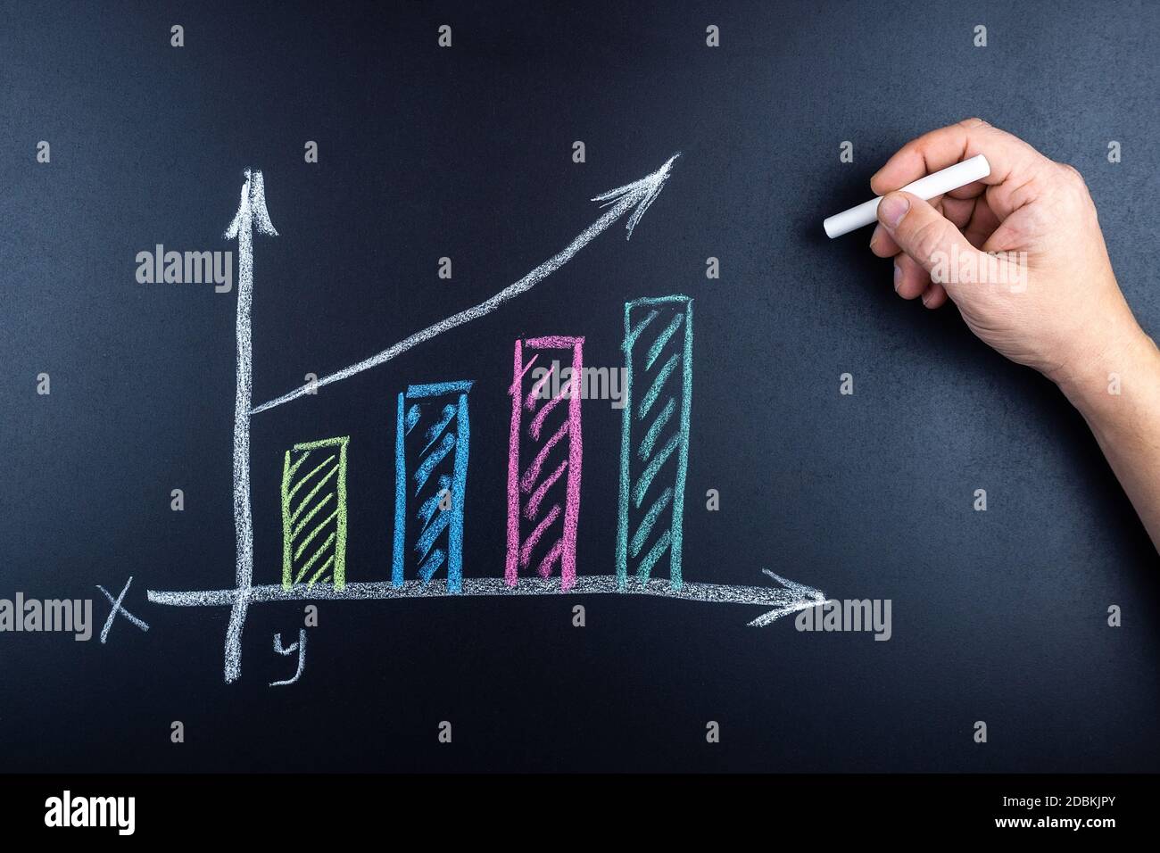 A man's hand with chalk draws an economic growth graph on a chalkboard ...