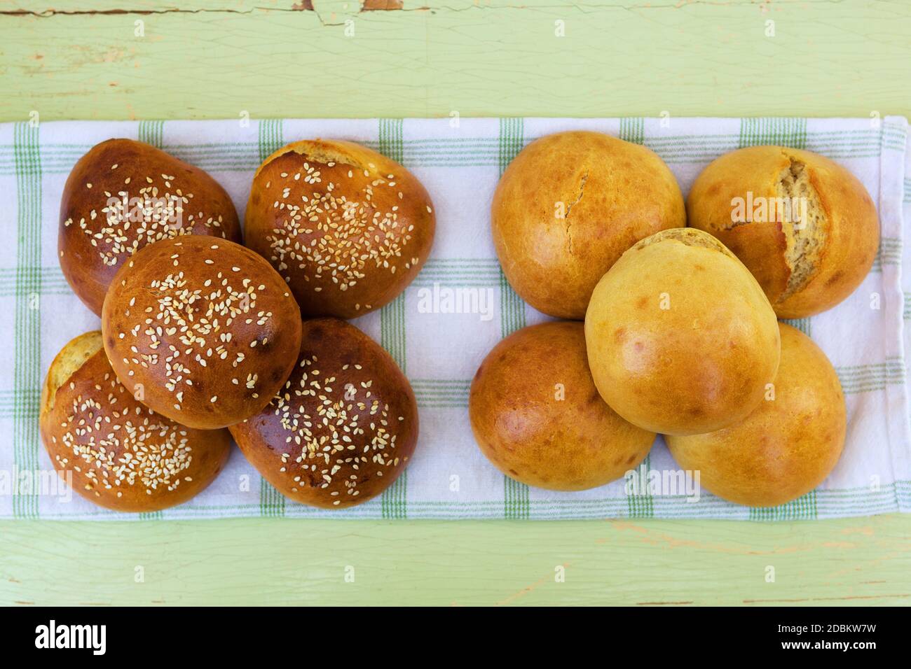 Burger buns with sesame on kitchen towel on table outdoor, top view ...
