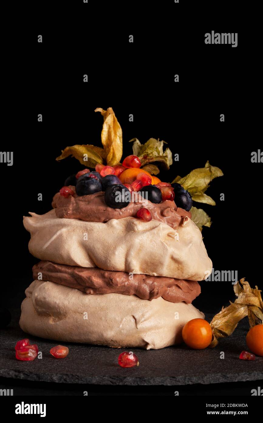 Pavlova dessert of meringue with mix fruit on dark background. Party ...