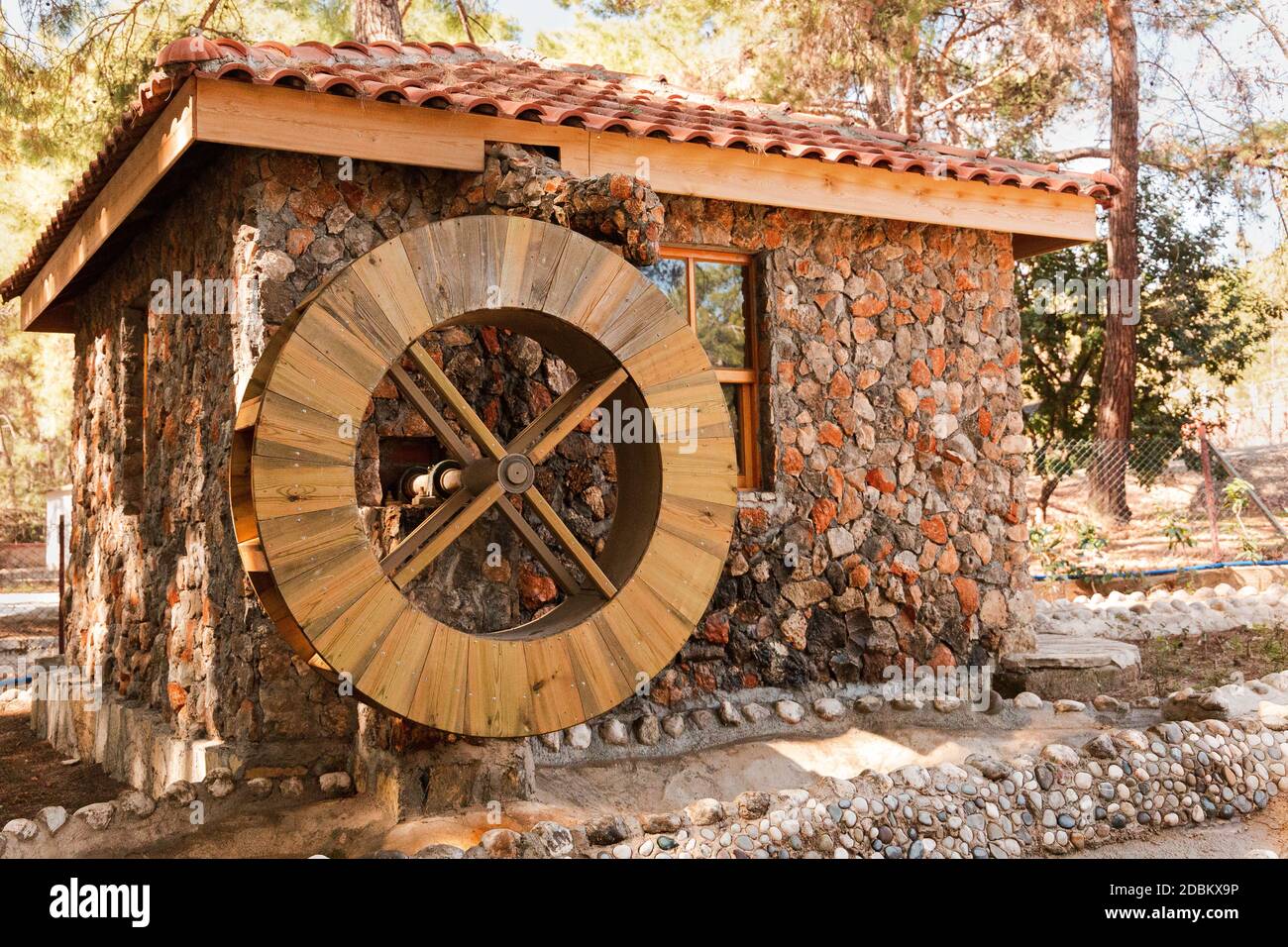 traditional stone house with tiled roof and wooden water mill on a ...