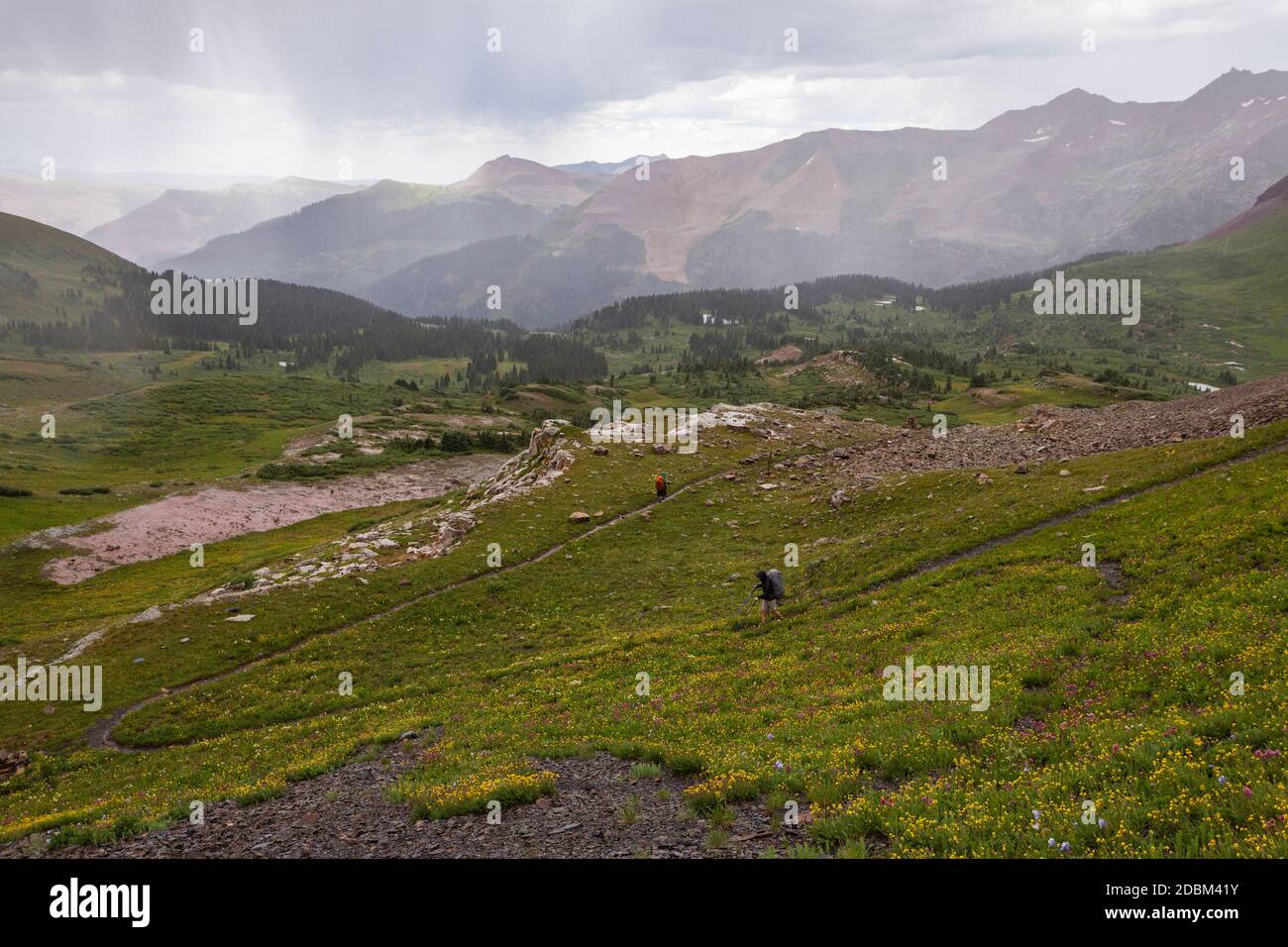 Two small hikers descending a pass through a storm on the Colorado ...
