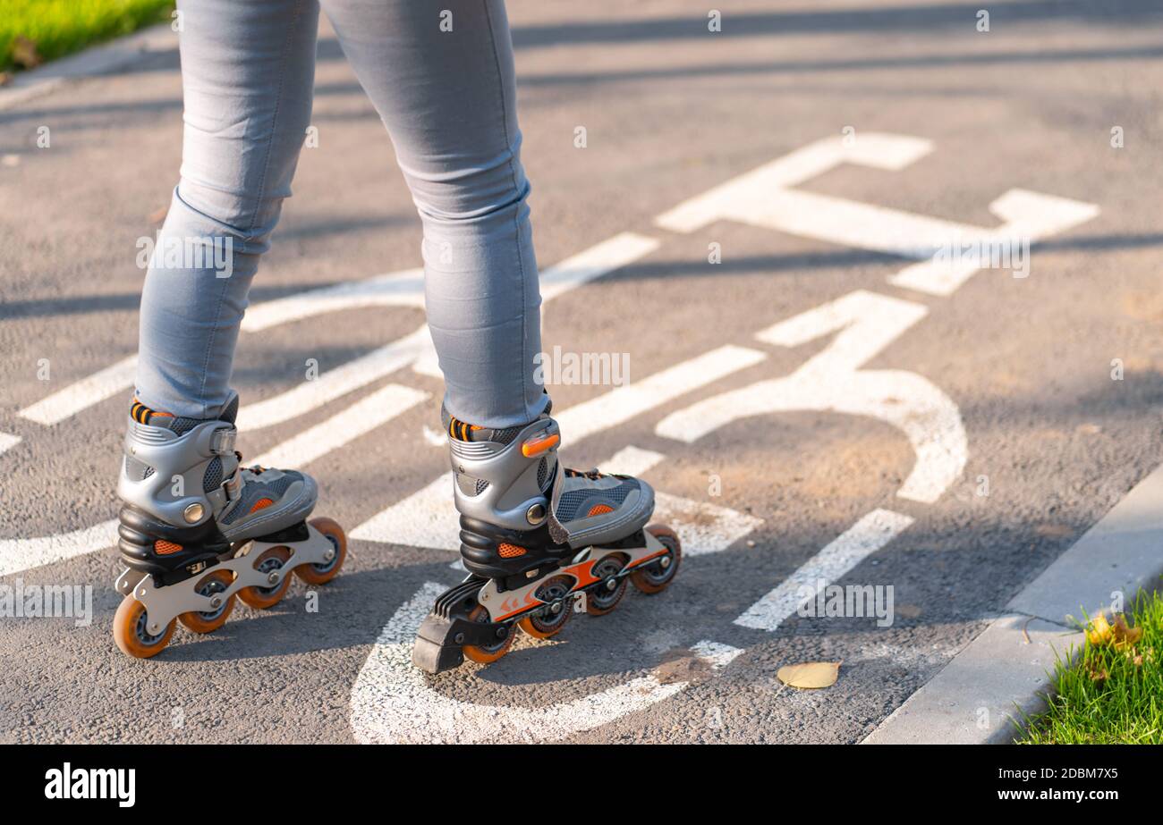 Active leisure. A sportive girl is rollerblading in an autumn park ...