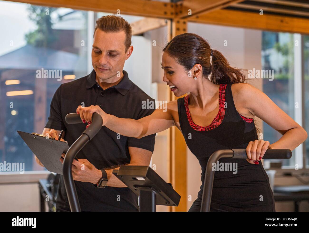 Personal trainer with client in gym Stock Photo - Alamy