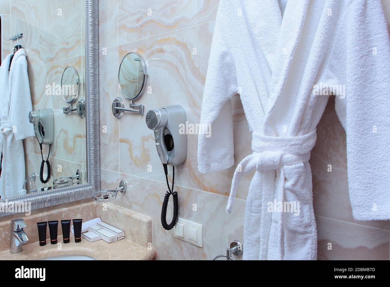 A white Terry robe hangs in the hotel bathroom. Photo in the interior ...