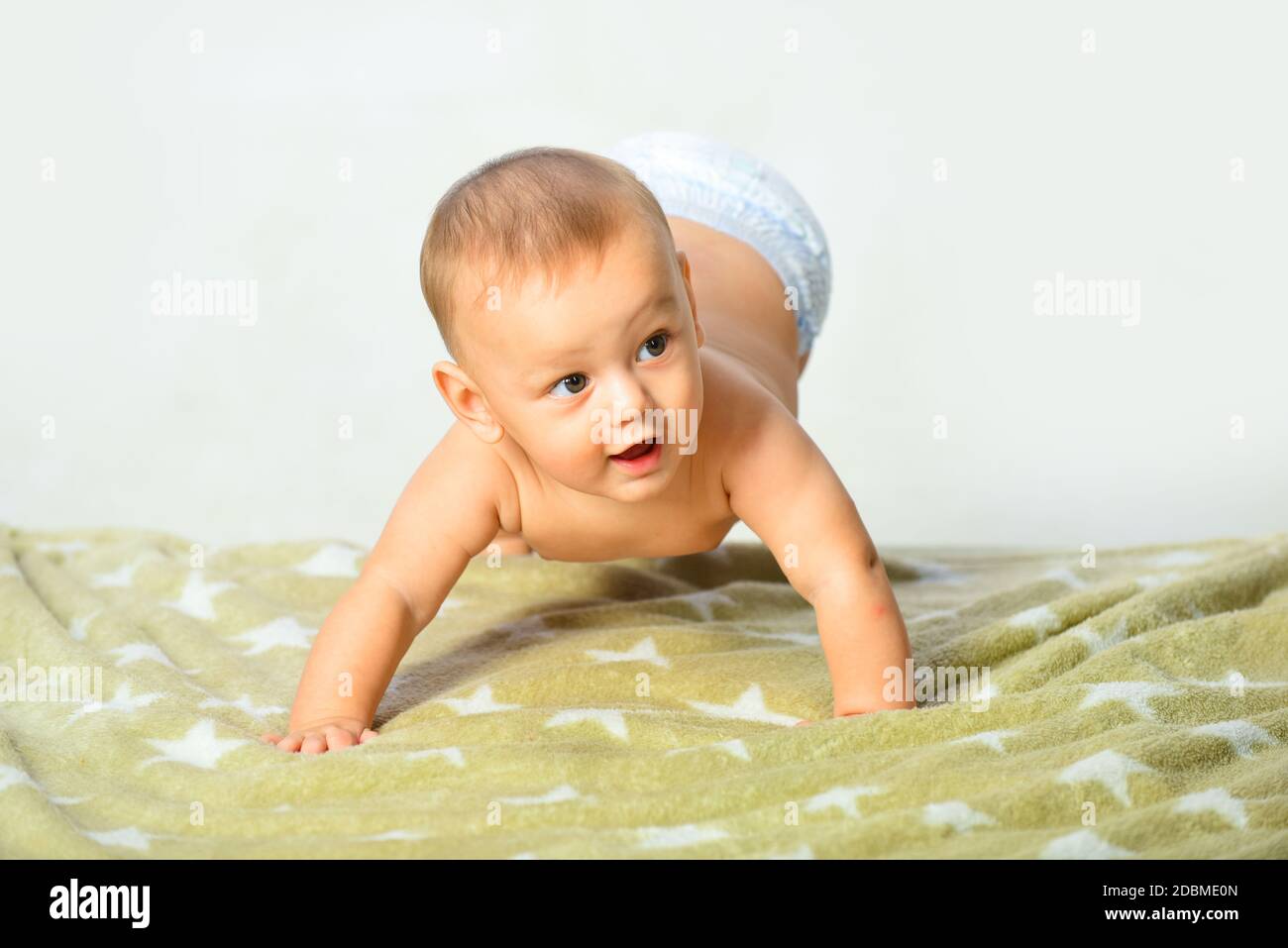 Newborn child relaxing in bed. Happy baby playing. Beautiful expressive ...
