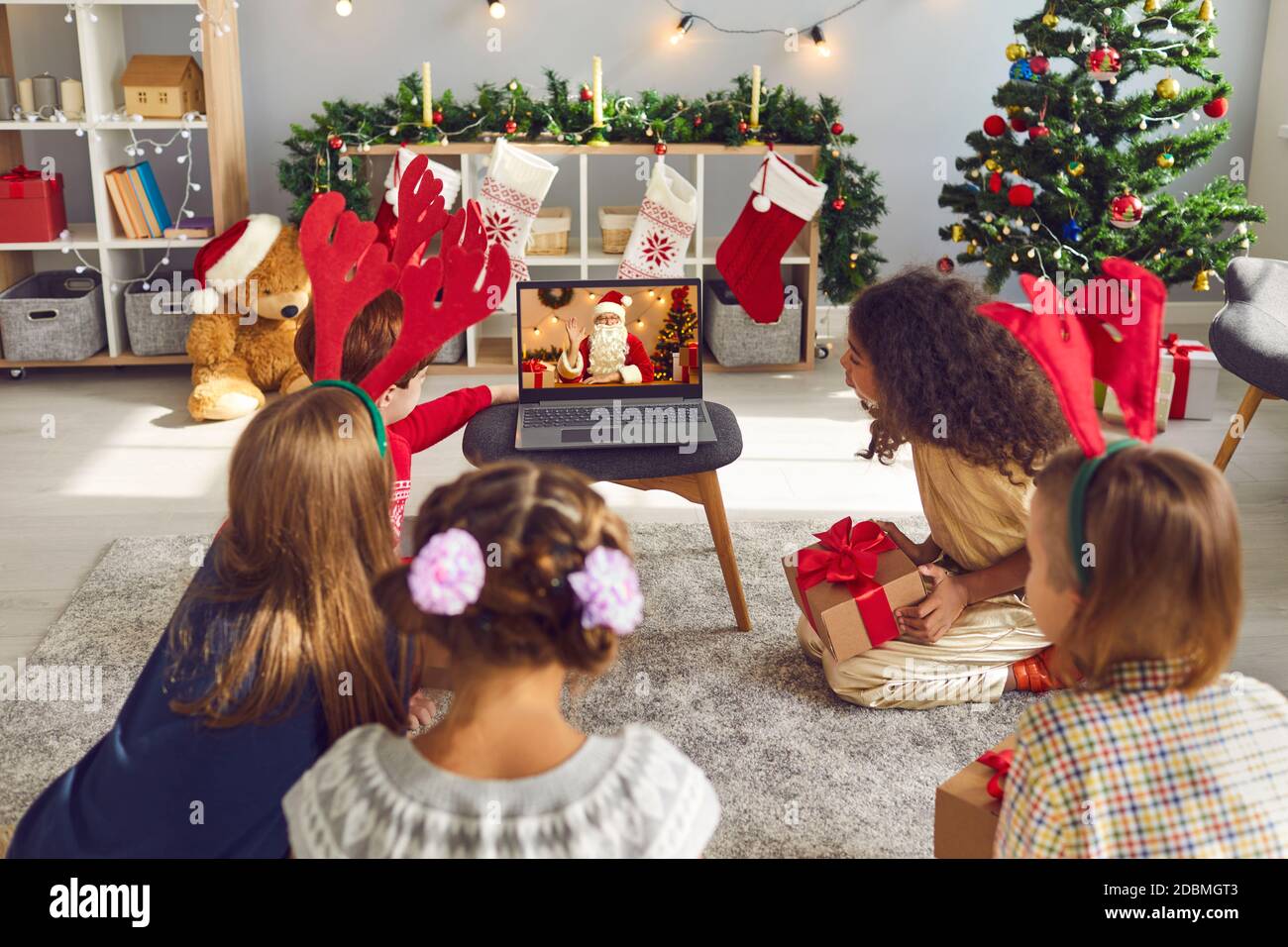 Group of kids gathering around laptop and video calling Santa Claus to ...