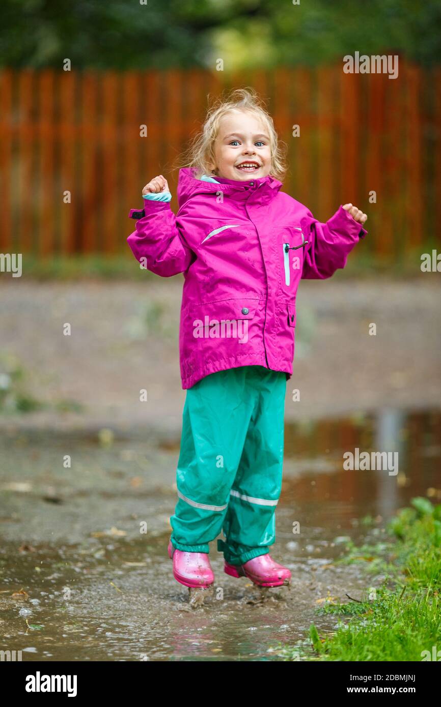 Happy little girl jumps into a puddle Stock Photo - Alamy