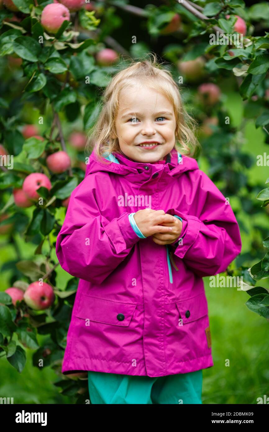 Little girl staying under apple tree in the garden Stock Photo - Alamy
