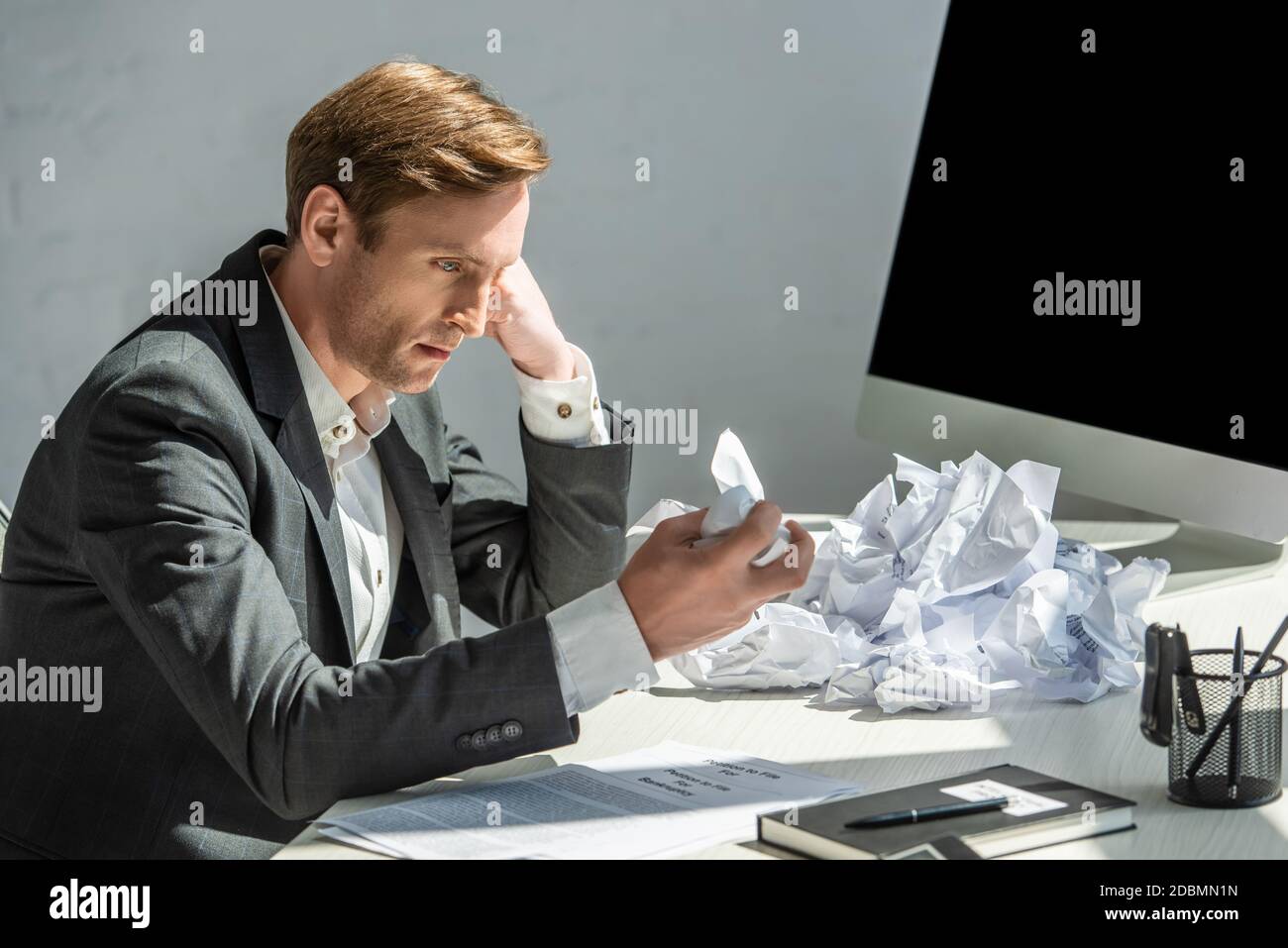 Disappointed businessman holding and looking at crumbled paper, while ...