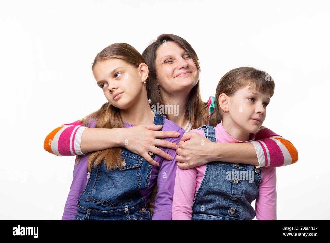 Mom happily hugs children, children turned away from mom Stock Photo ...