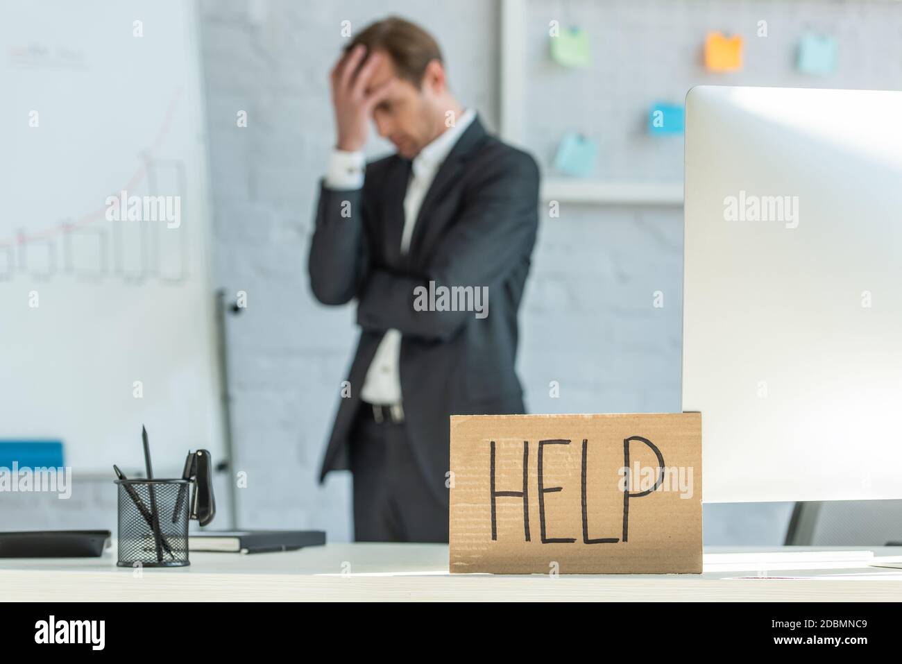 Cardboard with help lettering on workplace with blurred businessman on ...