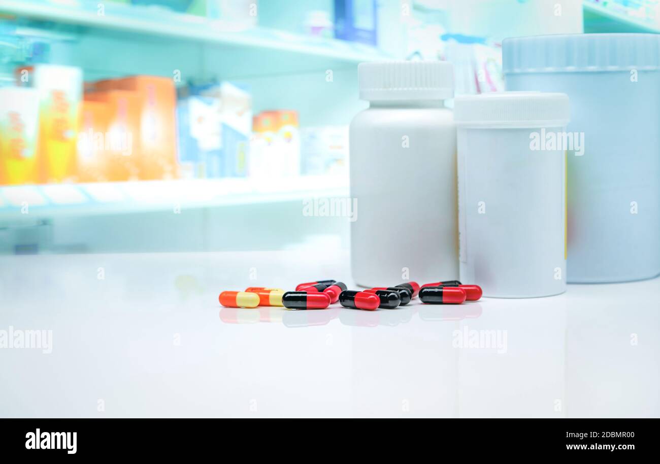 Capsule pills with drug bottles on white counter on blurred drug ...
