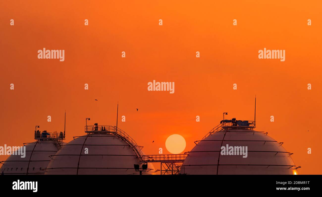 Industrial gas storage tank on orange sunset sky. LNG or liquefied ...