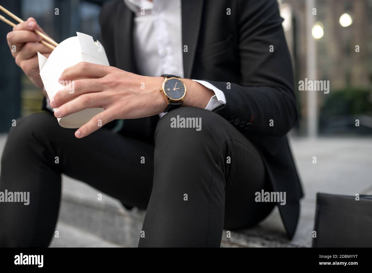 Close up picture of a man sitting on the steps and eating asian food ...