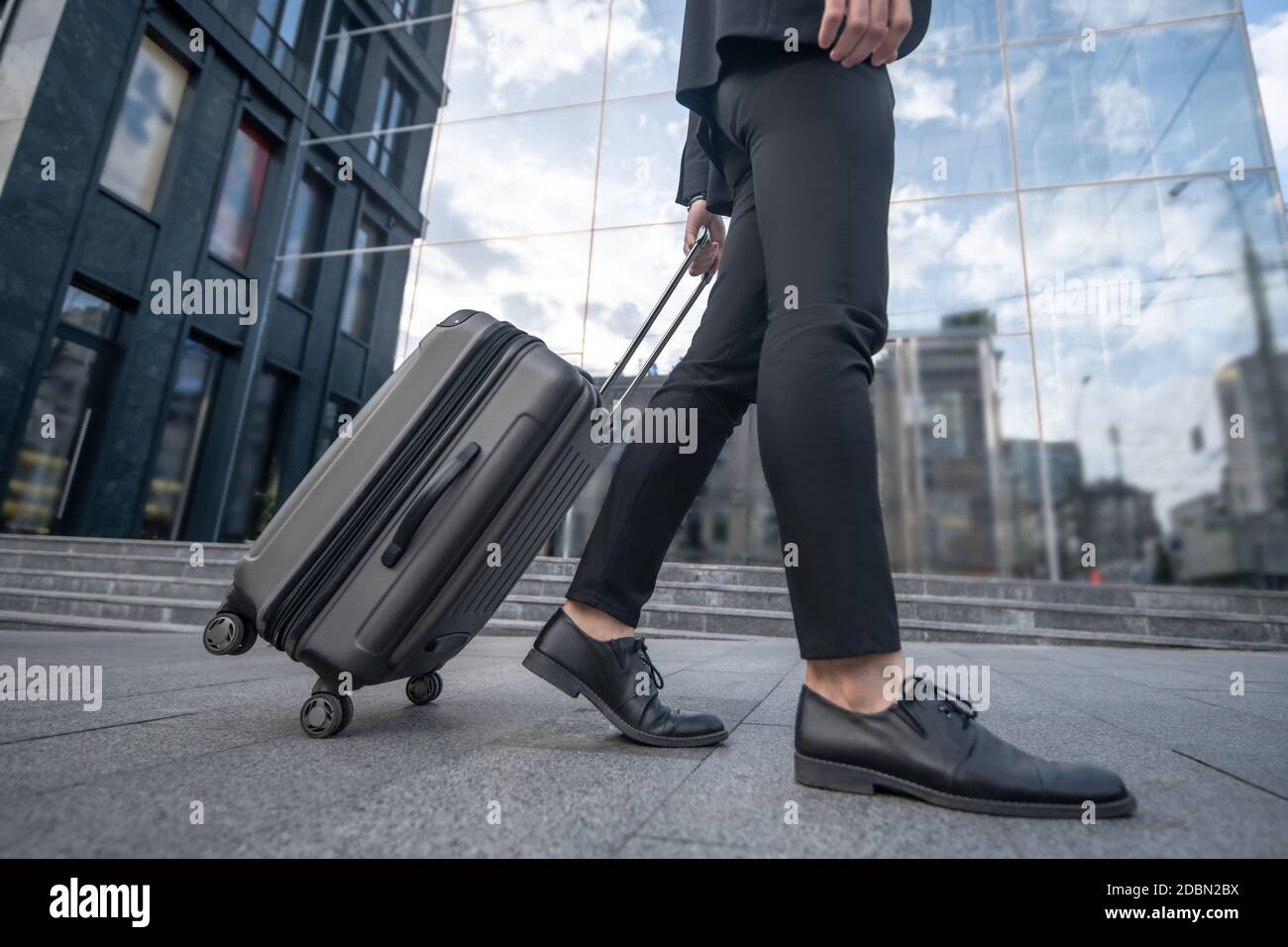 Close up picture of a man in a black suit carrying a suitcase Stock ...