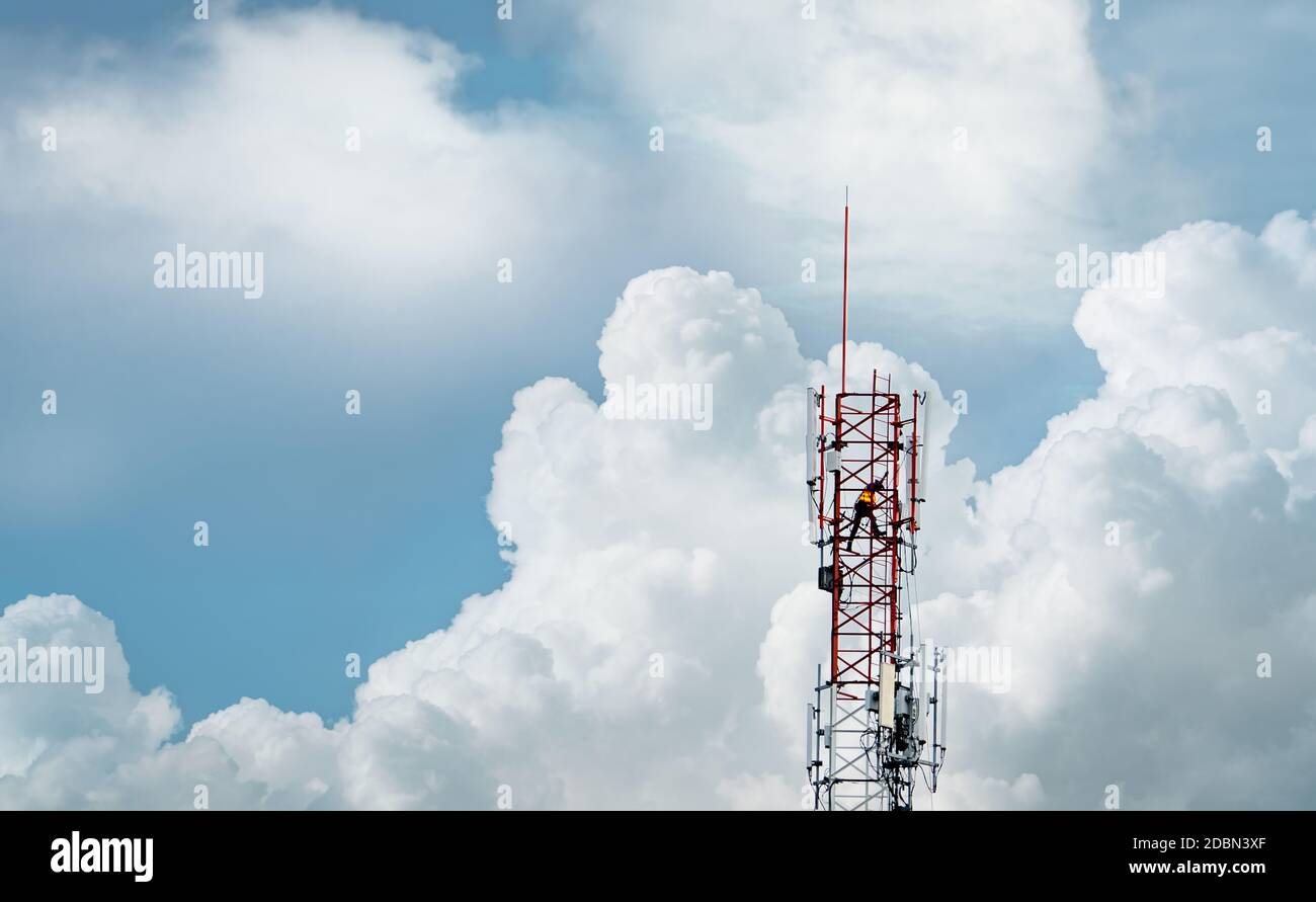 Telecommunication tower with blue sky and white clouds. Worker ...