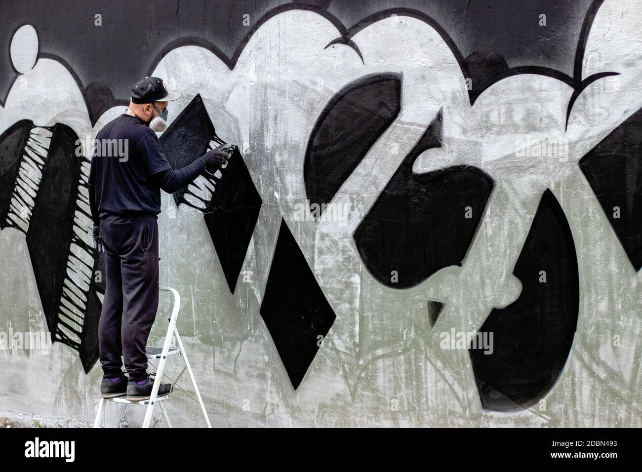 Graffiti artist in action, standing on ladders and wearing protective ...