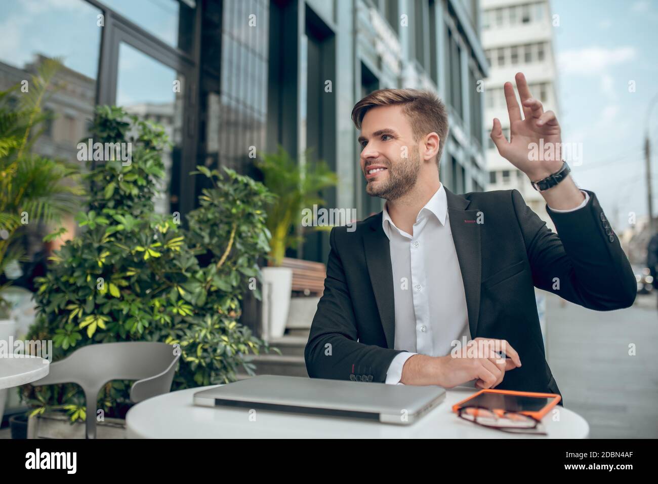 Handsome man raising his hand calling the waiter Stock Photo - Alamy