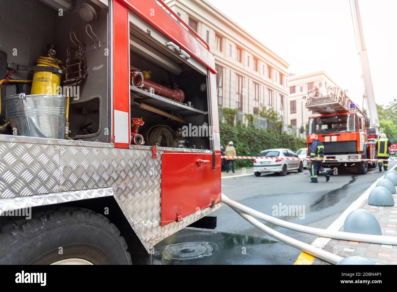 Firemen wearing uniform standing behind fire tape and many fire engine ...