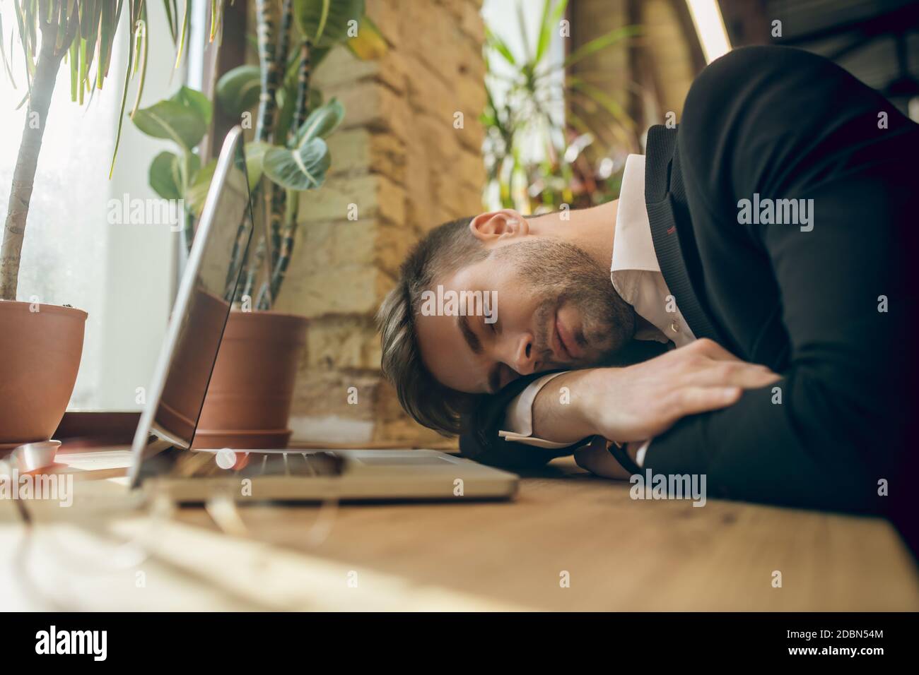 Young businessman in a black jacket napping in a cafe being tired after ...