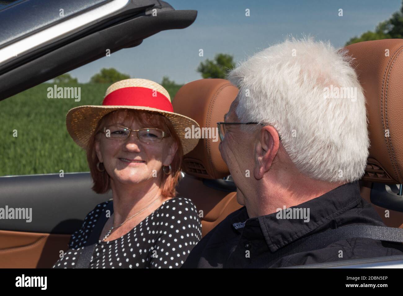 Happy older couple drives with a luxury sports car in the nature on a ...