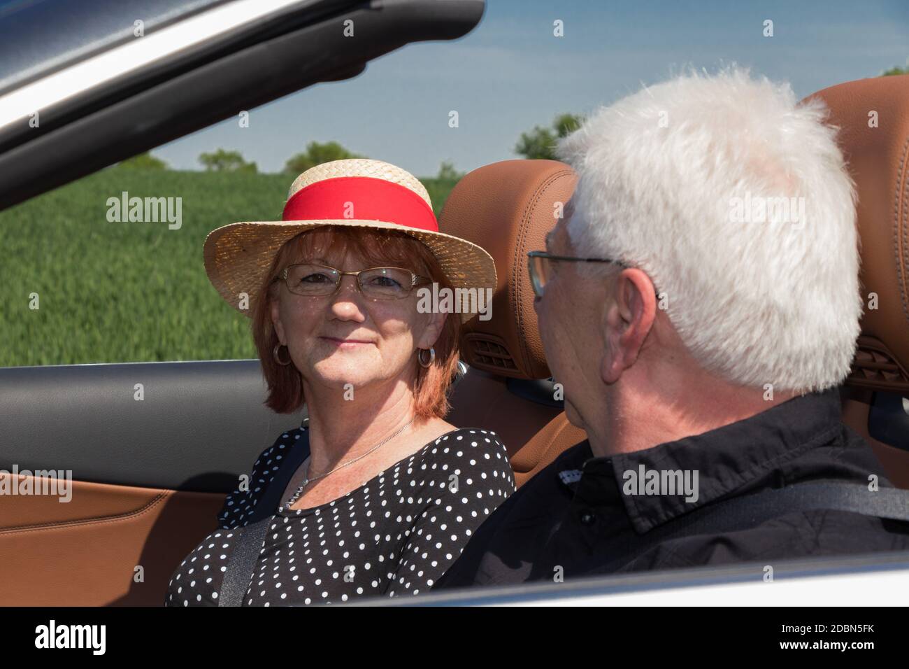 Two happy elderly people in a luxury convertible car on a sunny day ...