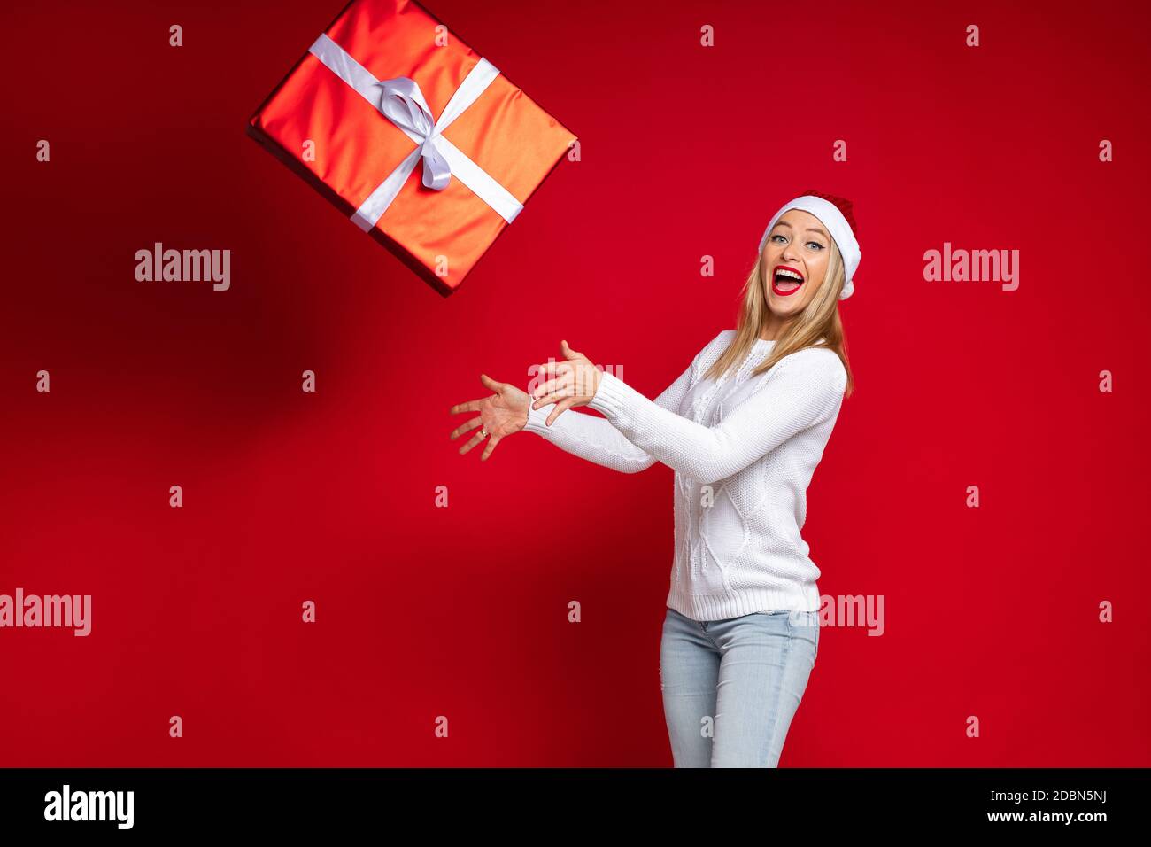 Happy girl throwing Christmas gift in studio Stock Photo - Alamy