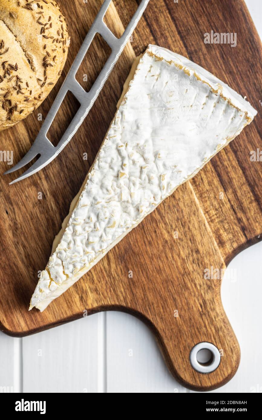Brie cheese. White soft cheese with white mold on cutting board. Top ...