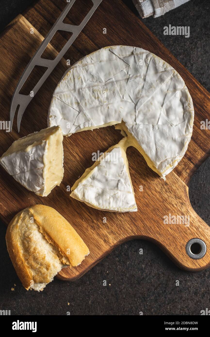 Brie cheese. White soft cheese with white mold on cutting board. Top ...