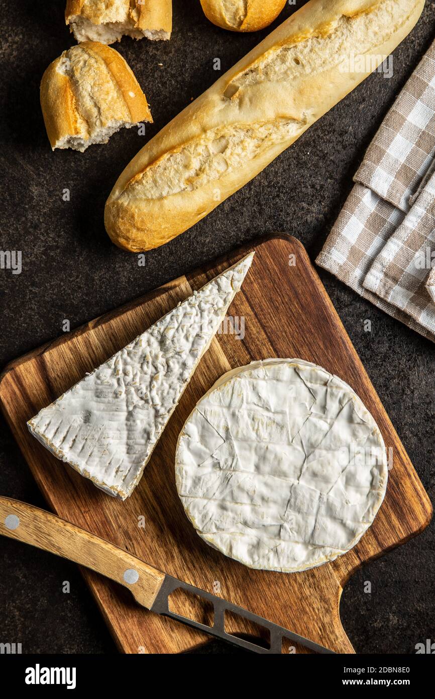Brie cheese. White soft cheese with white mold on cutting board. Top ...