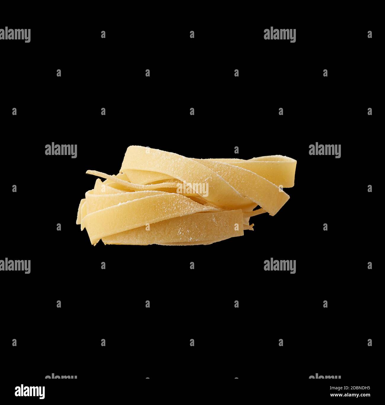 twisted pasta in a round fettuccine nest on a black isolated background ...