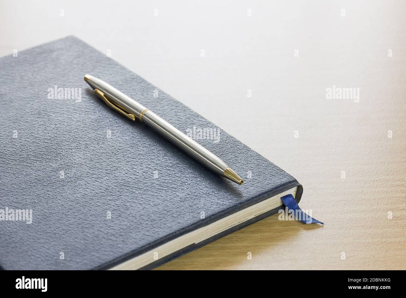 Pen on a book with deck wood background Stock Photo - Alamy