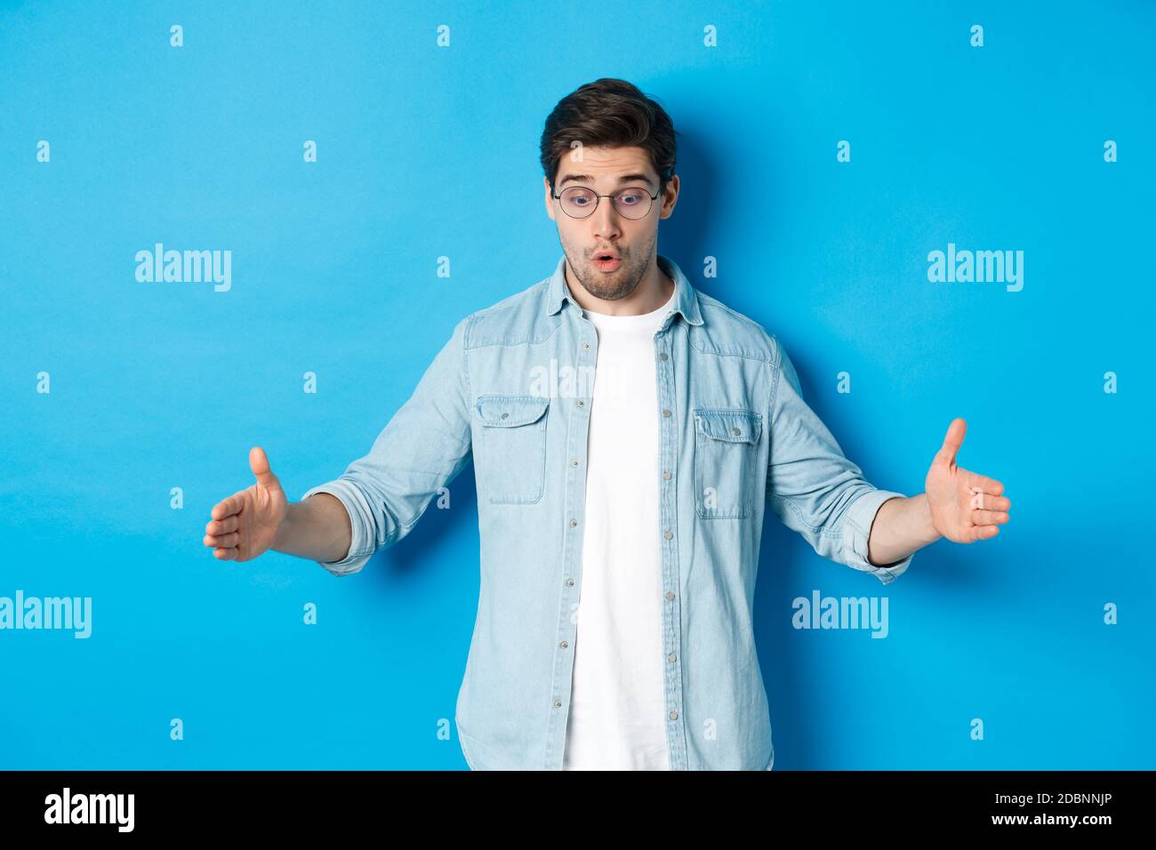 Excited handsome man showing big size object and looking amazed ...