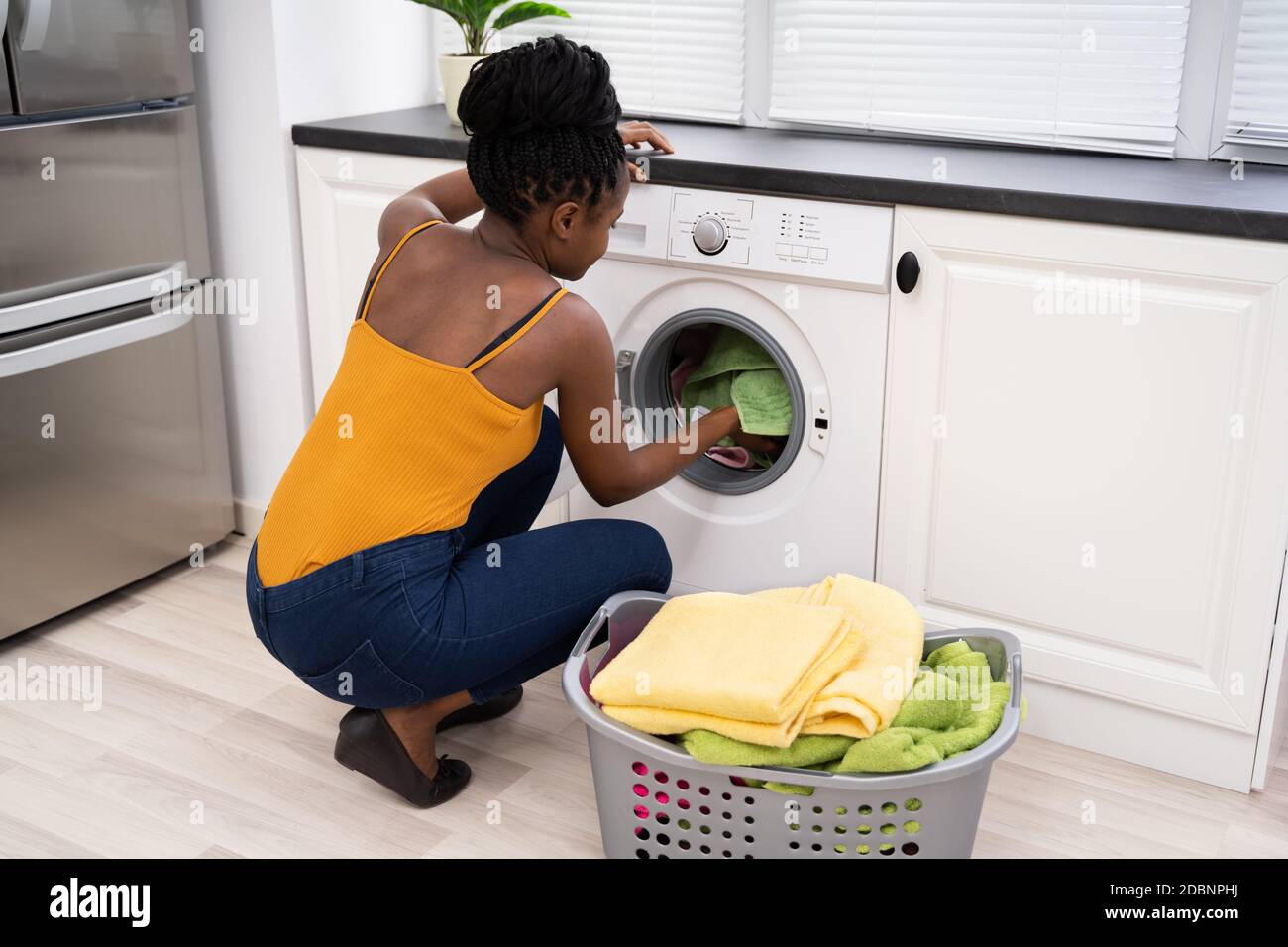 Woman Loading Dirty Clothes In Washing Machine For Washing In Utility ...