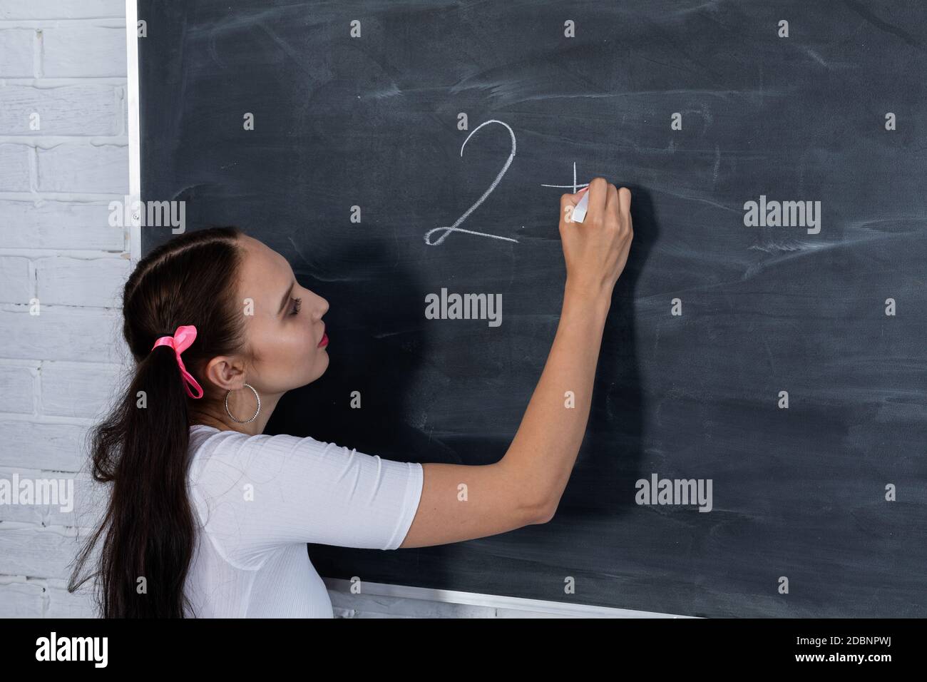 A young schoolgirl writes on the blackboard. School math lesson. He ...