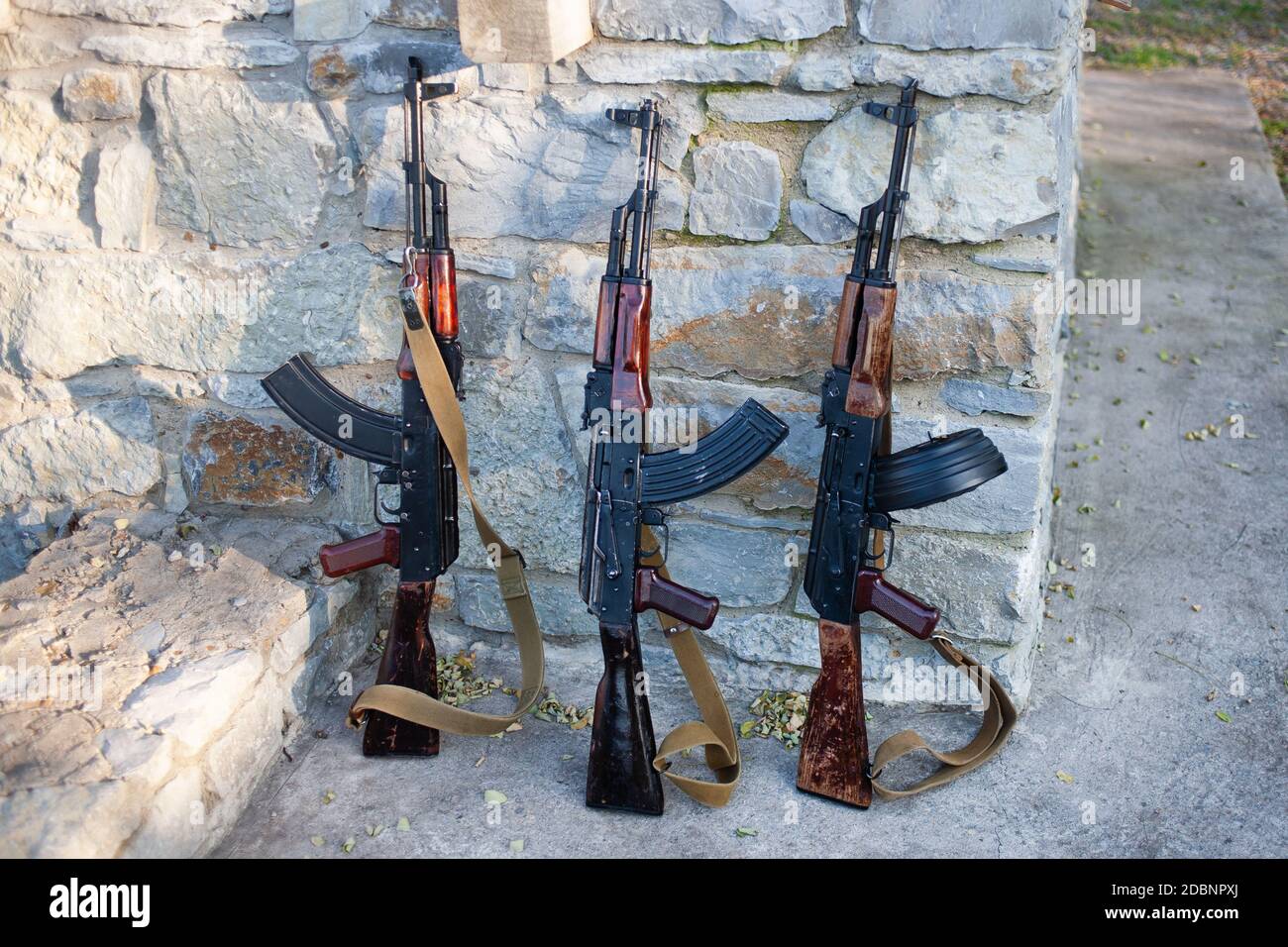 Three Kalashnikov AKM's near a stone wall Stock Photo - Alamy